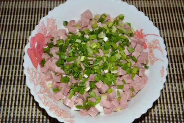 Cebolas verdes em um prato com cubos de presunto e outros ingredientes de salada de beijing repolho