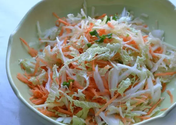 Beijing cabbage salad nga adunay mga karot, mansanas ug berde nga sibuyas sa usa ka dako nga panaksan