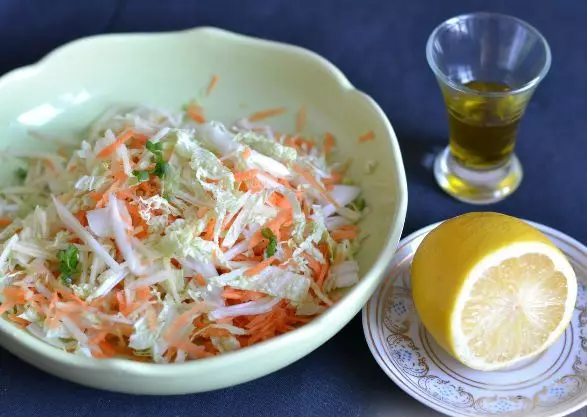 Salada de repolho de Pequim na tigela, limão em um pires e azeite em um copo