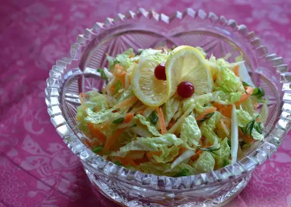 Beijing kool slaai met appel en wortels in 'n glas slaaiser op die tafel