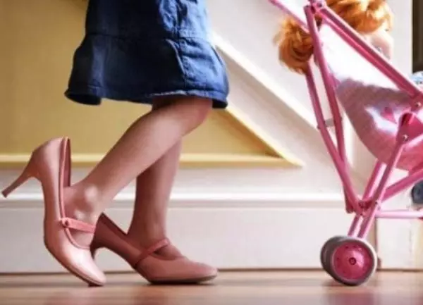 Момичето в големи розови обувки е щастлива играчка количка