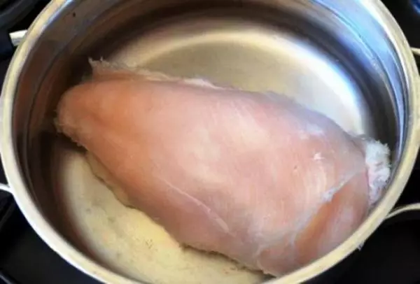Pechuga de pollo en una cacerola con agua.